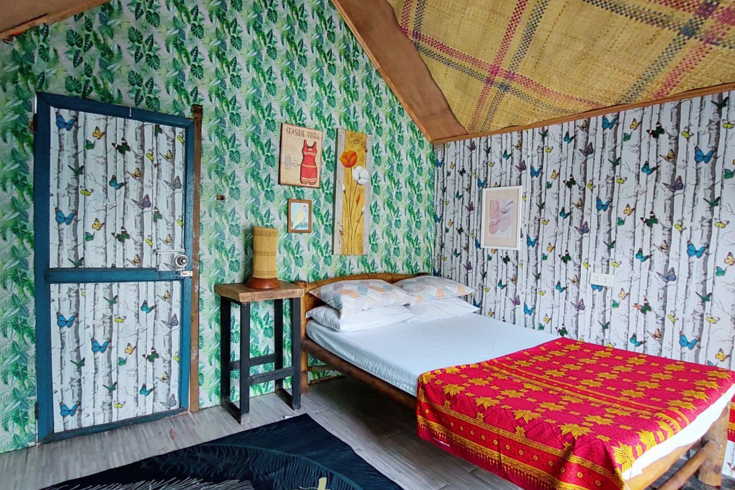 Quarto com cama, mesa de cabeceira e parede com papel de parede estampado.