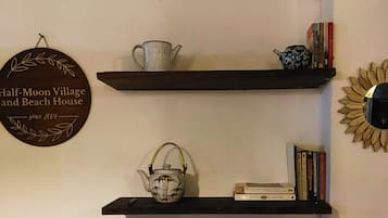 Duas prateleiras pretas fixadas na parede, com objetos decorativos, uma placa na parede e um enfeite de girassol.