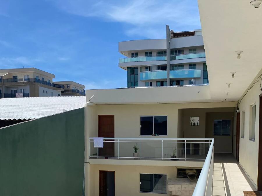 Um edifício com vários andares, varandas, área externa coberta e céu claro.