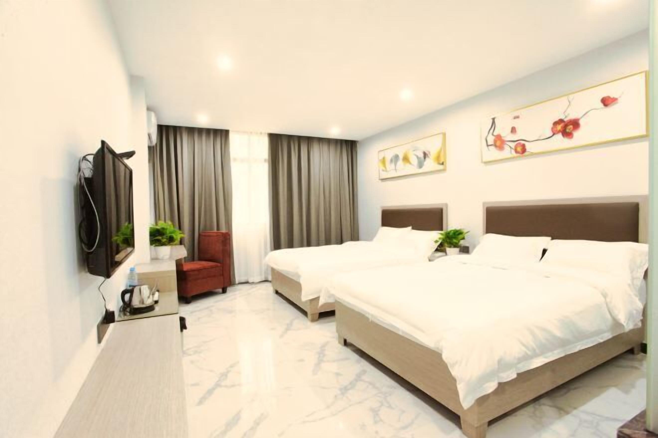 Quarto de hotel com duas camas, uma escrivaninha, uma cadeira, uma televisão e obras de arte nas paredes.