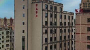 Um edifício de vários andares com fachada bege e sinalização vermelha indicando ser uma pensão.