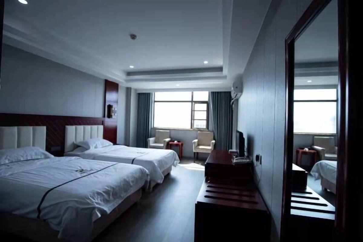 Quarto de hotel com duas camas, uma escrivaninha, uma cadeira e uma televisão.