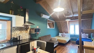 Um quarto acolhedor e rústico, com cozinha, mesa de jantar e cadeiras, e uma cama em mezanino.