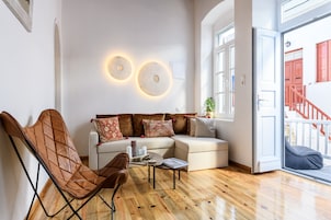 Uma sala de estar moderna com sofá, uma poltrona de couro marrom, mesa de centro e piso de madeira.