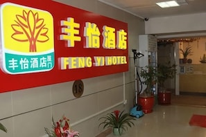 Placa de hotel com logotipo de árvore e o nome 'FENG YI HOTEL' em chinês e inglês.