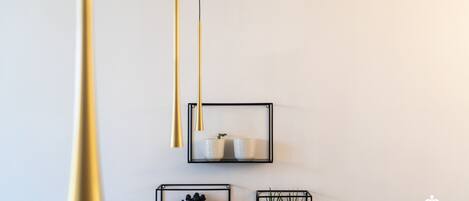 Três prateleiras de parede com moldura preta, adornadas com objetos decorativos e plantas em vasos.