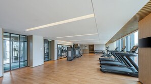 Uma academia ampla com esteiras, aparelhos de musculação e um espelho grande.