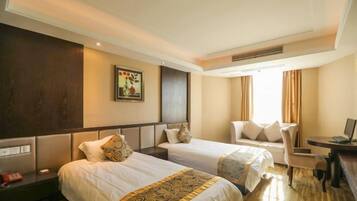 Quarto de hotel com duas camas, uma mesa, uma cadeira e um quadro na parede.