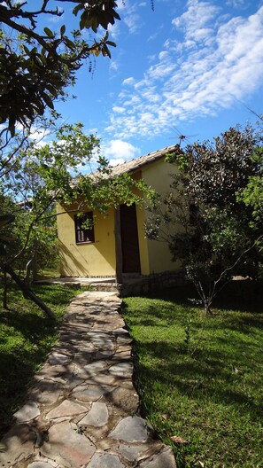 Um edifício amarelo com um caminho de pedra que leva a uma porta escura.