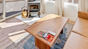 Sala de estar moderna com uma grande janela, lareira e vista para uma casa e paisagem.