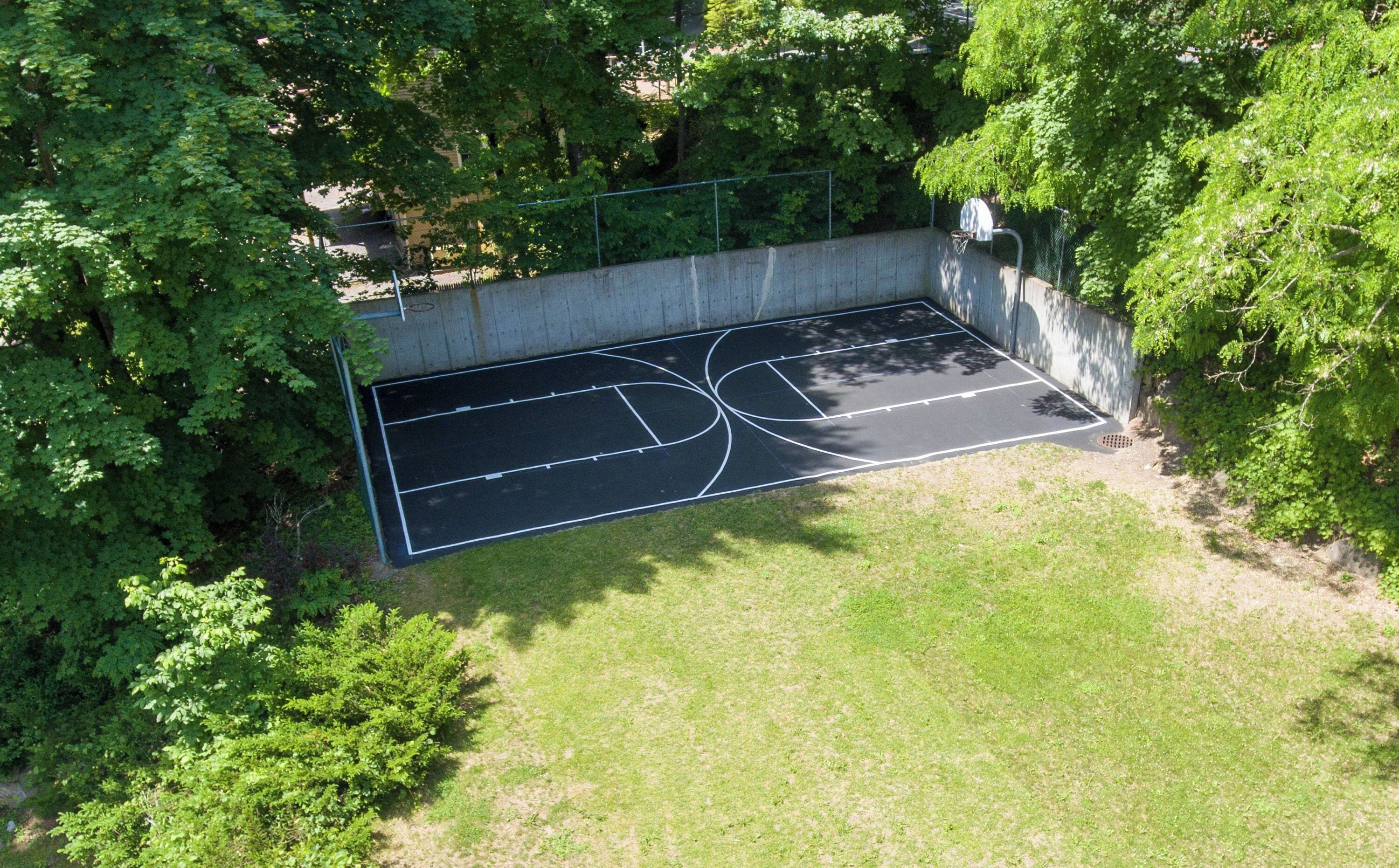 Quadra de basquete ao ar livre rodeada por árvores.