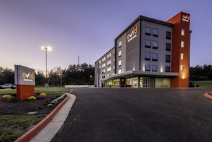 Um edifício moderno de hotel com telhado plano, várias janelas e uma placa indicando ser o Avid Hotel.