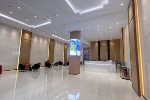 Um saguão de hotel com balcão de recepção, área de estar e um quiosque de informações digitais.