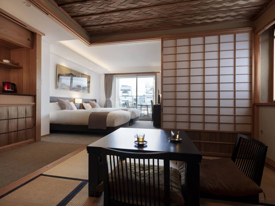 Um quarto tradicional japonês, com piso de tatame, uma mesa baixa com almofadas e um painel deslizante shoji.