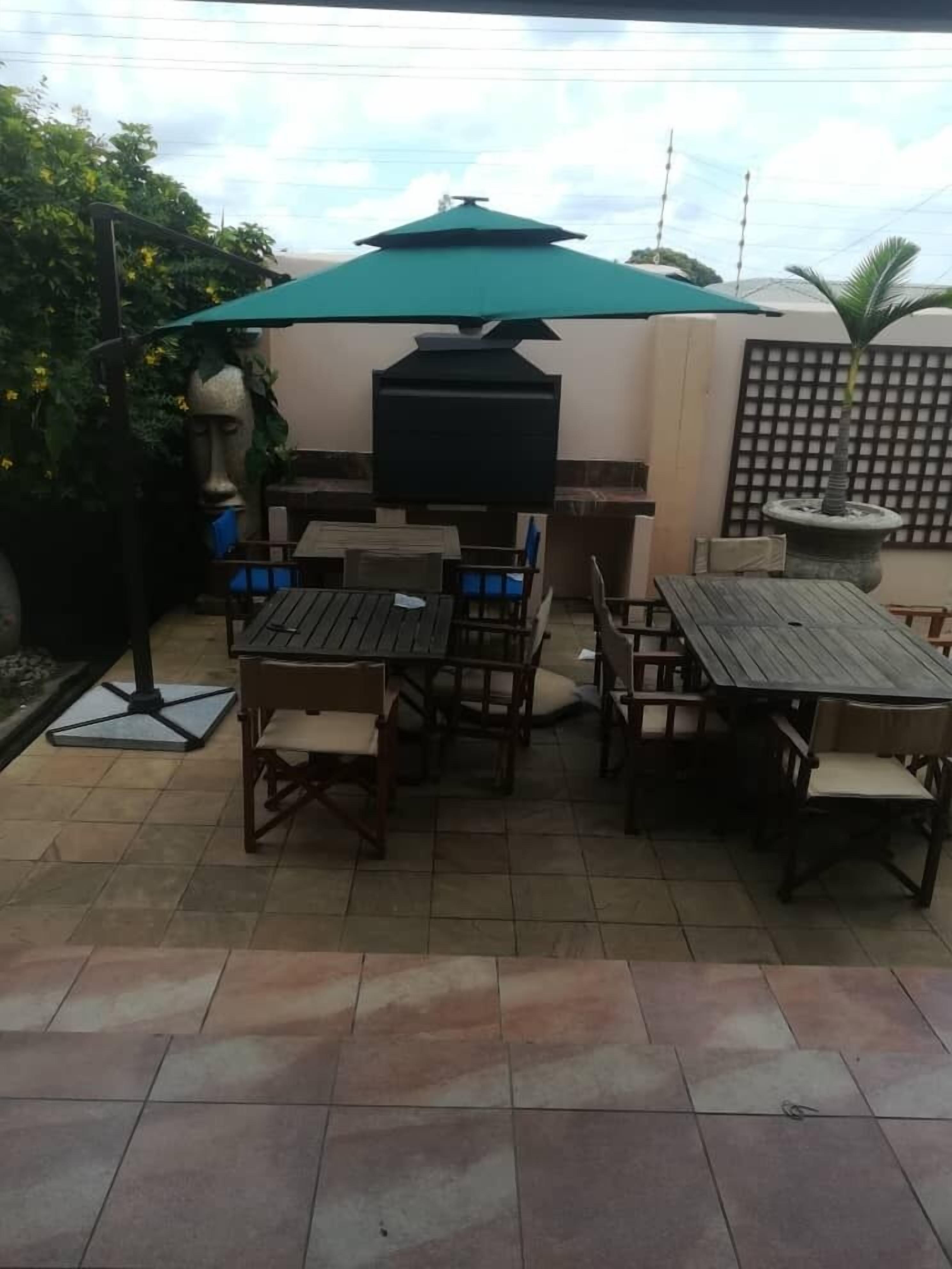 Um pátio externo com churrasqueira, mesa de jantar e cadeiras.