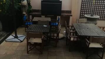 Um pátio externo com churrasqueira, mesa de jantar e cadeiras.