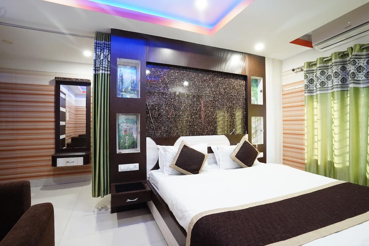 Quarto moderno com uma cama grande, cômoda, espelho e TV fixada na parede.
