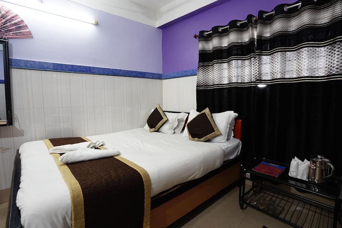 Quarto de hotel com cama, almofadas, toalha, mesa de cabeceira e cafeteira.
