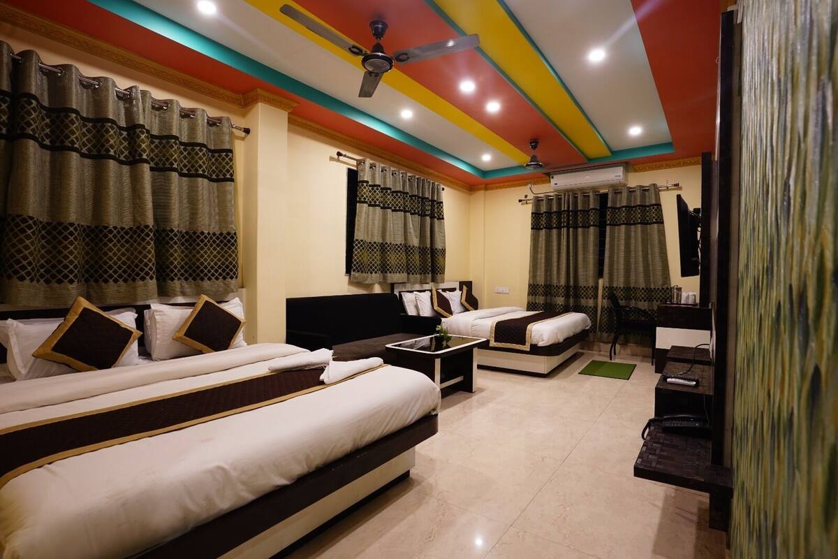 Quarto de hotel com duas camas, uma escrivaninha e um ventilador de teto.