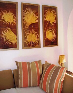 Uma sala de estar com um sofá, almofadas listradas e três obras de arte emolduradas na parede.