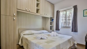 Quarto com cama, guarda-roupa de madeira e janela com cortinas.