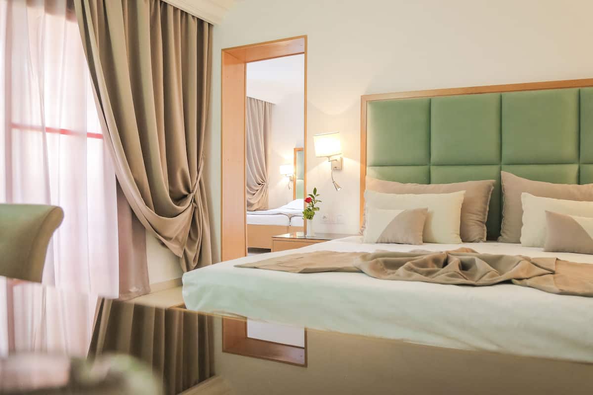 Quarto de hotel com uma cama grande, mesa de cabeceira, espelho e uma cadeira.