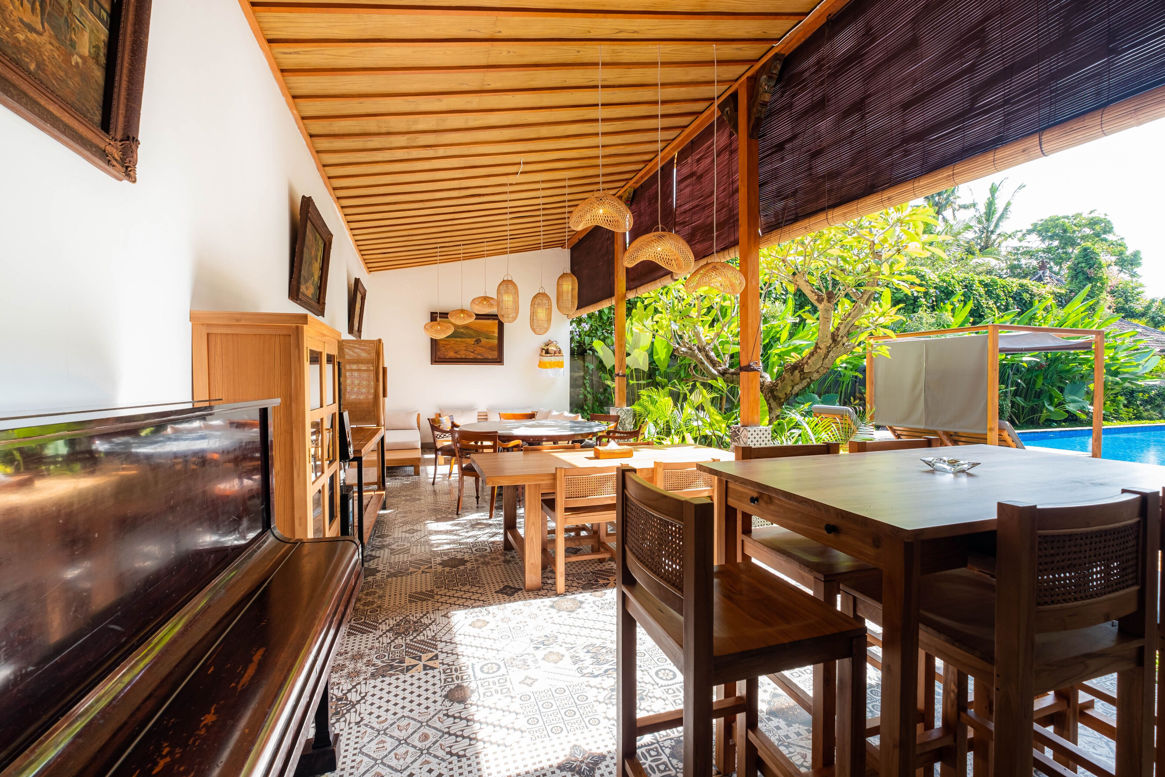 Um restaurante com mobiliário de madeira, piso estampado e vista para o verde.