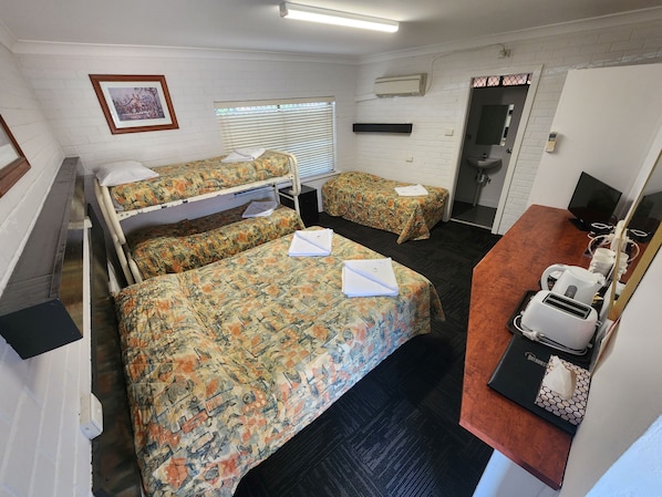 Quarto com duas camas, uma escrivaninha com computador, pia e ar condicionado.