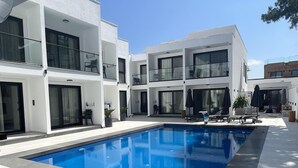 Um edifício residencial moderno com piscina, janelas amplas e telhado plano.
