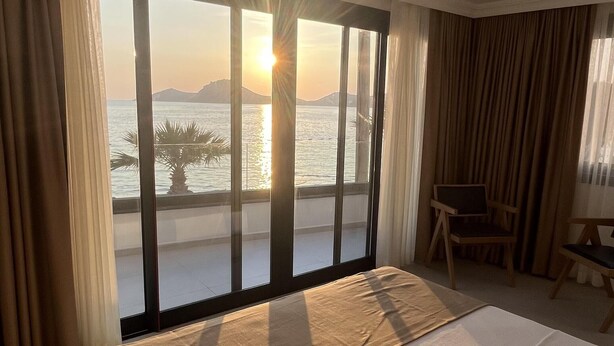 Quarto com uma cama grande, vista para o mar e varanda.