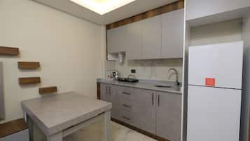 Uma cozinha compacta com bancada de mármore, pia embutida e frigorífico branco.