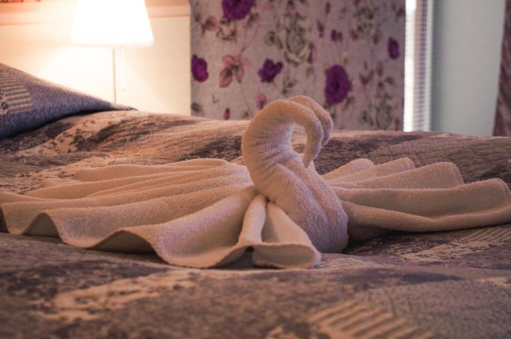 Toalha dobrada sobre a cama, com colcha de padrão floral.