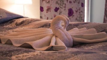 Toalha dobrada sobre a cama, com colcha de padrão floral.