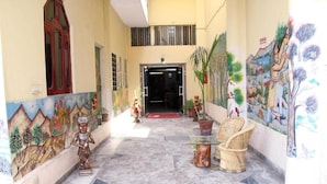 Um corredor com piso de azulejos, uma porta no final e um mural nas paredes.