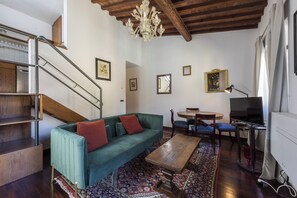 Uma sala de estar com sofá, mesa de centro, TV e um espaço de jantar com cadeiras e mesa.
