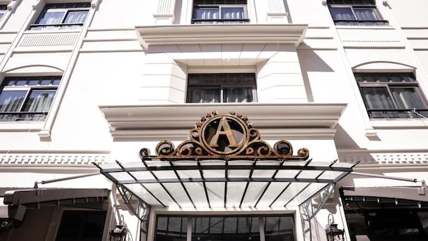 Fachada de prédio com um grande logotipo 'A', amplas janelas e entrada coberta.