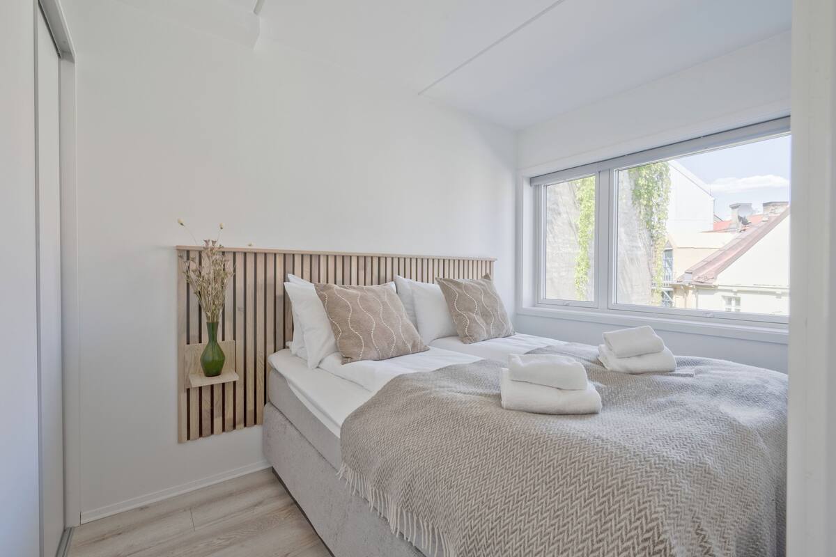 Um quarto moderno com cama, janela e prateleira na parede com um vaso.