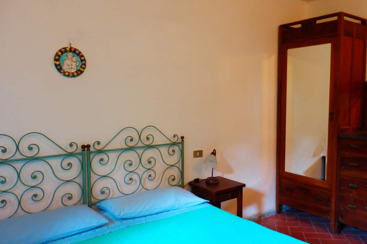 Quarto com uma cama, penteadeira, espelho e um adorno na parede.