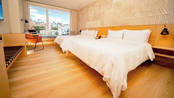 Quarto de hotel moderno com uma cama grande, uma escrivaninha e vista para a cidade.