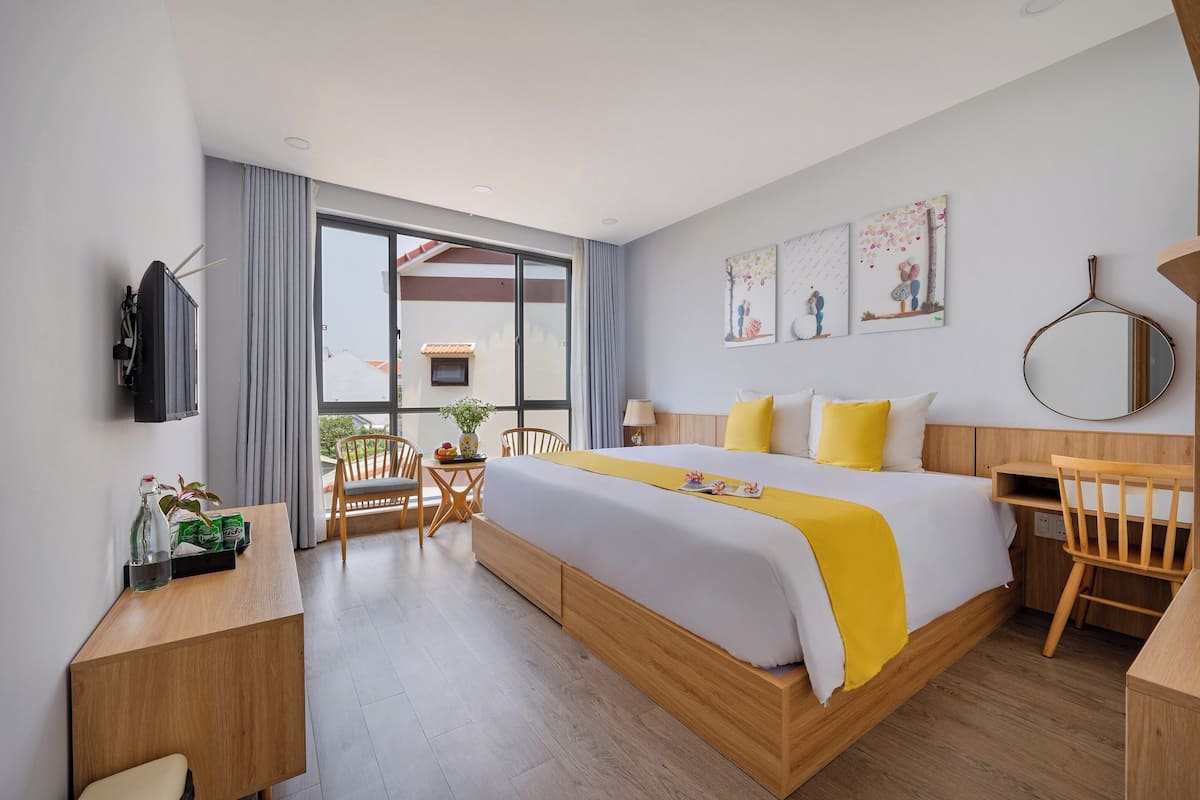 Quarto de hotel moderno com uma cama grande, uma mesa de escritório e varanda com vista.