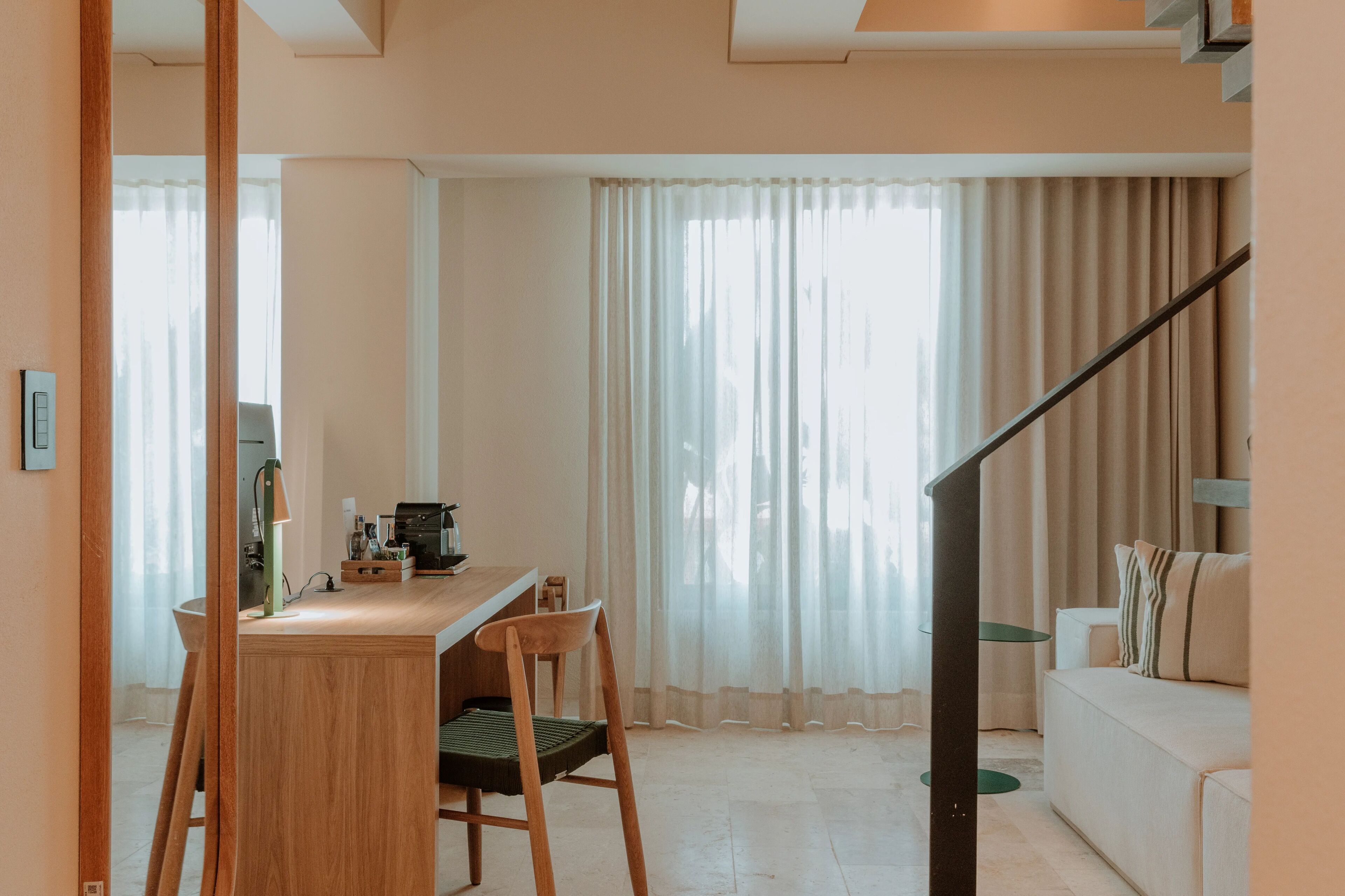 Uma sala de estar moderna com uma mesa de jantar de madeira, um sofá e uma escada.