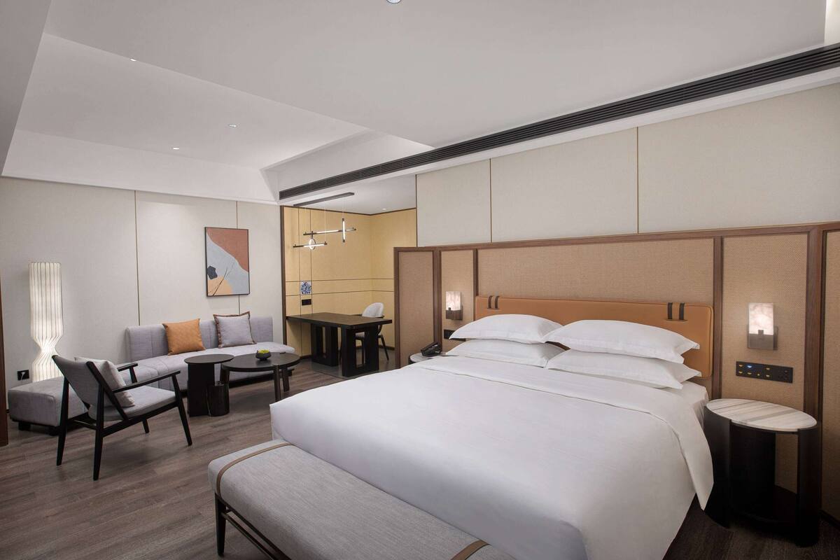 Quarto de hotel com uma cama grande, um sofá, uma escrivaninha e uma cadeira.