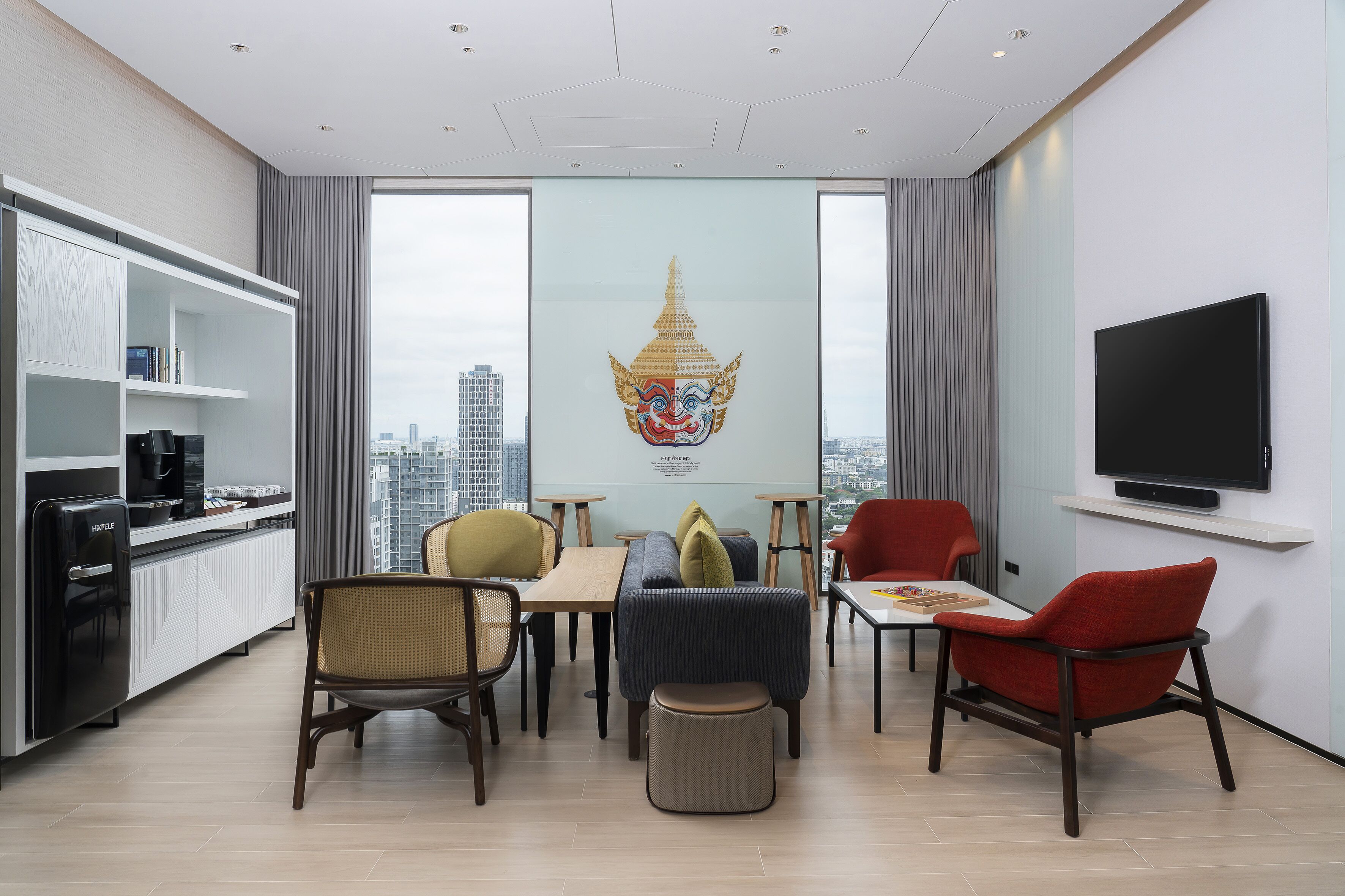 Quarto de hotel moderno com vista para a cidade, cozinha compacta, área de refeições e televisão na parede.