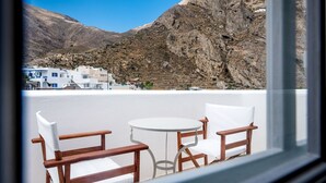 Um terraço com mesa e cadeiras, com vista para uma paisagem montanhosa com edifícios brancos.