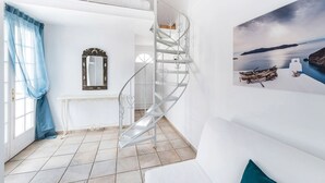 Uma escadaria em espiral com corrimão branco, uma parede branca com um espelho emoldurado, uma cortina azul e uma pintura de um barco em mar calmo.