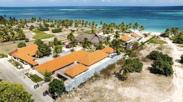 Vista aérea de um resort com vários edifícios, palmeiras e uma praia.