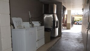 Uma lavanderia com máquina de lavar, secadora e uma grande geladeira de aço inoxidável.