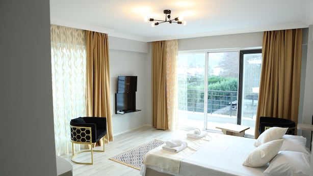 Quarto de hotel moderno com uma cama grande, uma TV, uma cadeira e vista para o exterior.