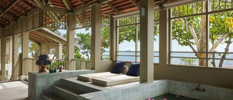 Uma área de spa com piscina, escadas para um espaço de estar e vista para o mar.