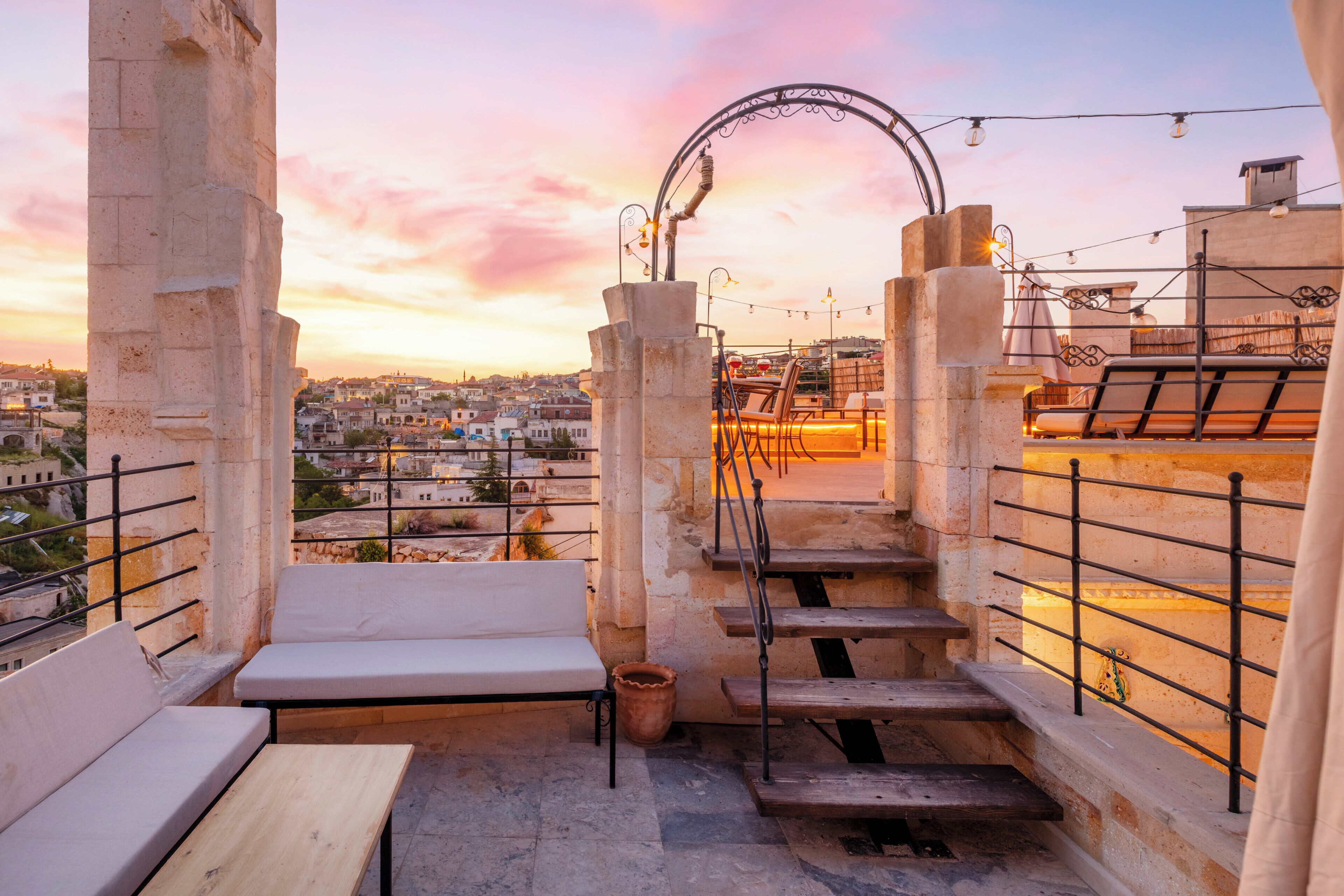 Terraço no telhado com área de estar, escadas e vista para a paisagem urbana.